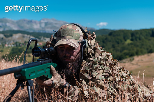 Army soldier holding sniper rifle with scope and aiming in forest. War ...