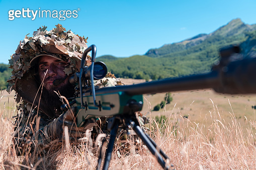 Army soldier holding sniper rifle with scope and aiming in forest. War ...