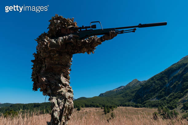Army soldier holding a sniper rifle with scope and walking in the ...