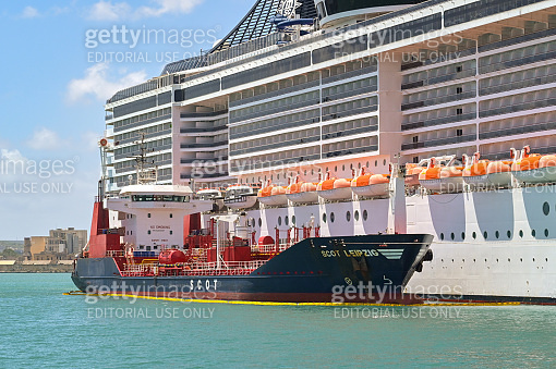 Small oil tanker alongside a large cruise ship for refuelling 이미지 ...