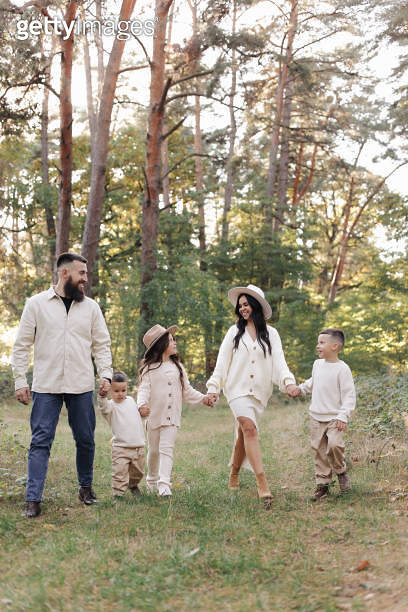 Young mother, father with daughter and sons are walking, having fun in autumn forest. Family ...
