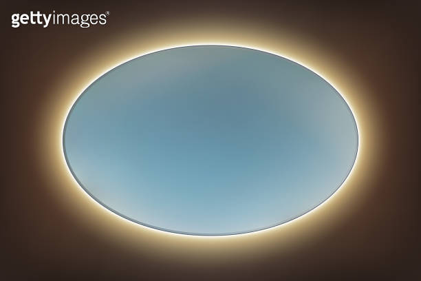 Oval mirror with rounded corners with yellow LED backlight on a dark ...