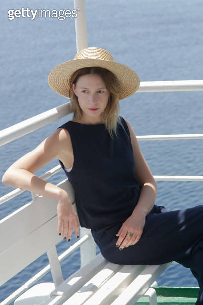 Stylish tourist woman in blue linen outfit and straw hat travelling on ...