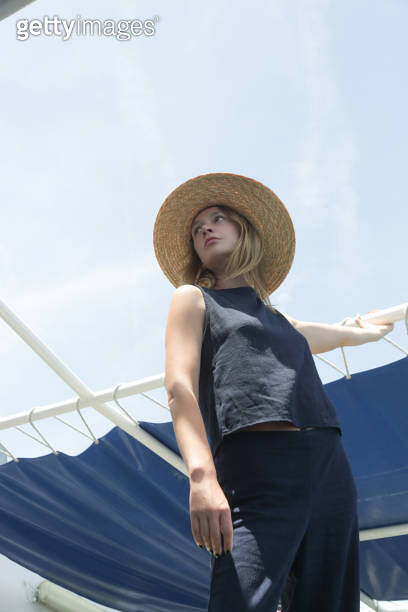 Stylish tourist woman in blue linen outfit and straw hat travelling on ...