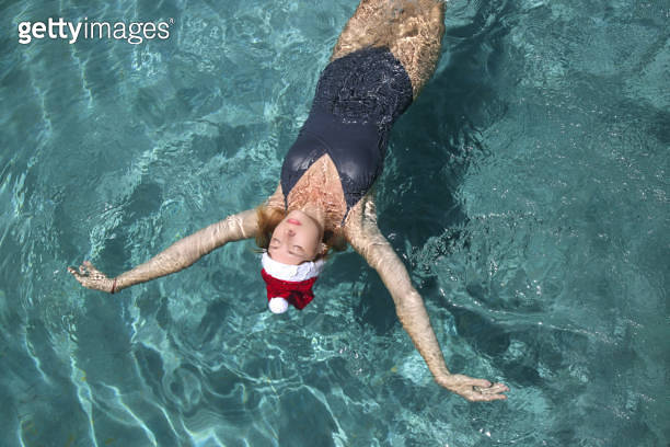 Young woman in santa hat relaxing in swimming pool. Christmas tropical ...