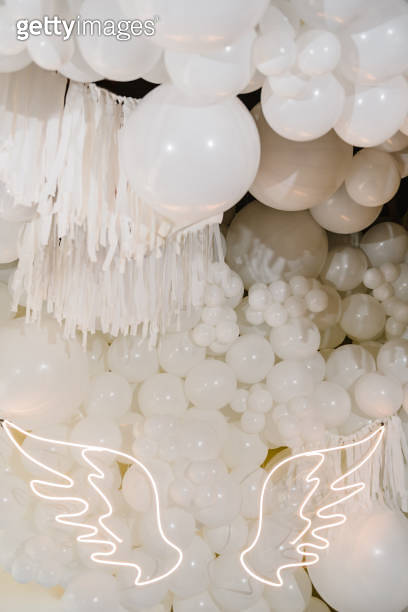 Wall decorated white balloons, angel wings for a baptism. Photo area decoration space, place ...