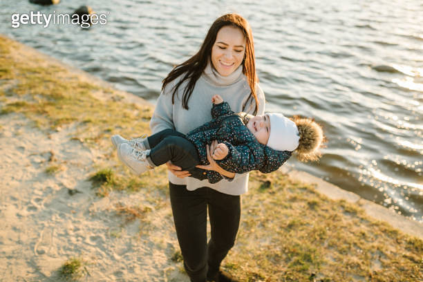 Mother throws child, flying in sky near lake in nature. Family spending ...