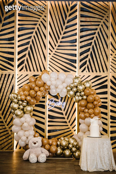 Arch decorated with brown, white and golden balloons, text baby. Trendy cake with figure angel ...