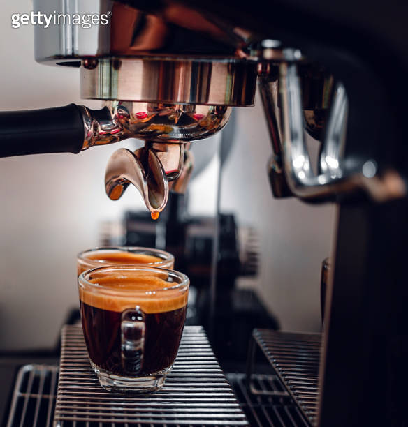 Professional espresso machine while preparing two espressos shot in a coffee shop. Close-up of ...