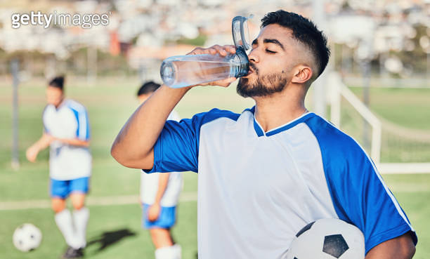 Football, athlete and man drinking water outdoor on a sports field for ...