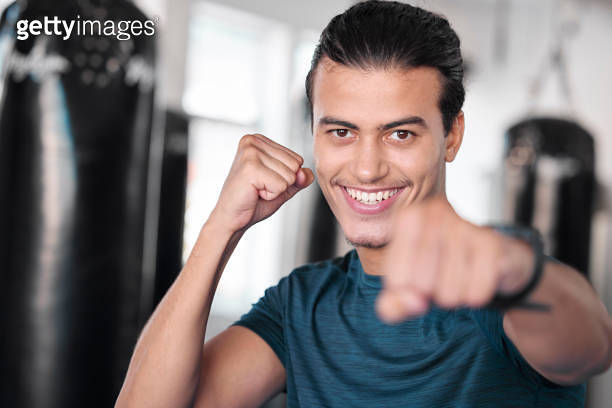 Portrait, boxer punch and smile of man in gym ready to start workout ...
