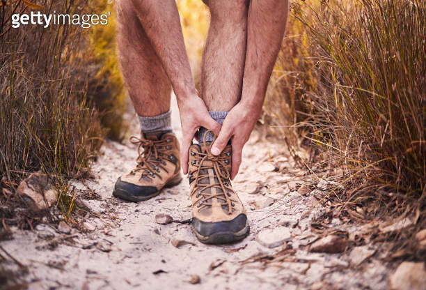 Hiking, injury and shoes of man in nature for leg pain, training and ...
