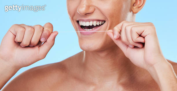 Happy man, dental floss and cleaning teeth in oral hygiene or grooming against a blue studio ...