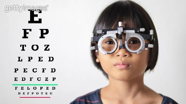 Elementary school girl wearing eyeglasses visual acuity test with test ...