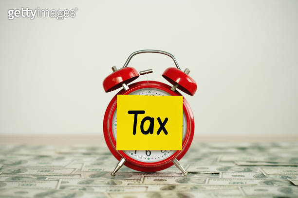 tax post-it on the Red alarm clock on money banknotes. Tax and Vat ...