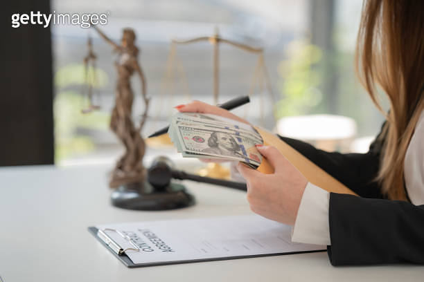 Selective focus, a woman offering a batch of hundred dollar bills ...