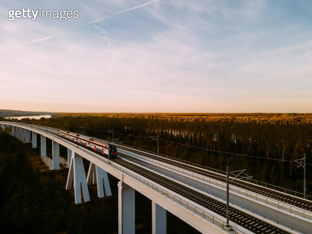 Modern railway viaduct in nature. Passenger train crossing the bridge ...