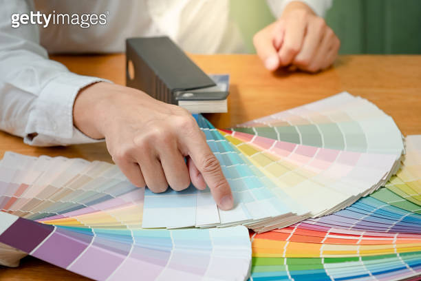 Designer hand choosing and pointing at color swatch samples catalog or ...