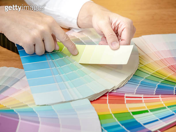 Designer hand choosing and pointing at color swatch samples catalog or ...