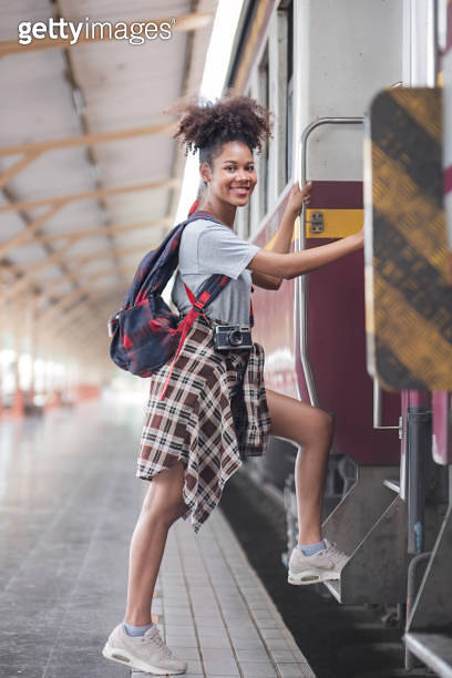 Traveler african asian american woman getting in a train to hop on ...