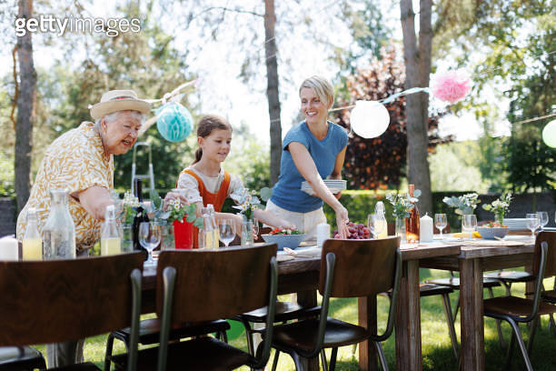 Grandmother, mother and daughter setting table for summer garden party ...