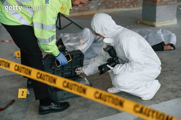 Caution police tape. Detectives are collecting evidence in a crime ...