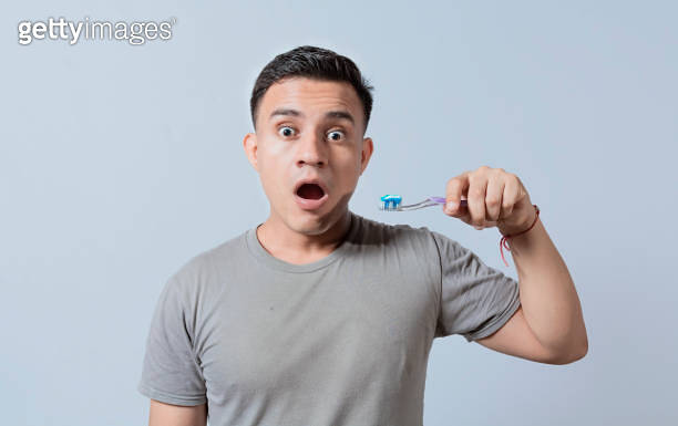 Amazed young man holding toothbrush with toothpaste isolated, guy with ...