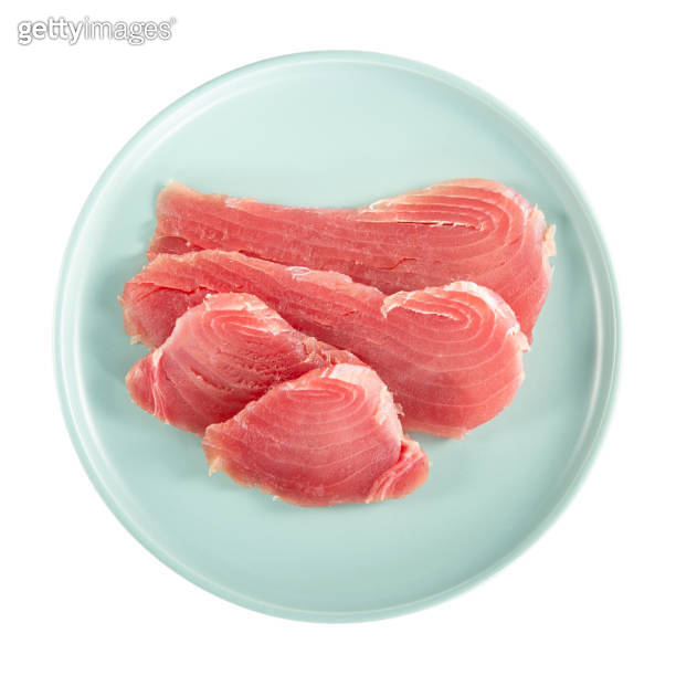 Slices of cold smoked tuna on blue plate isolated on white background ...