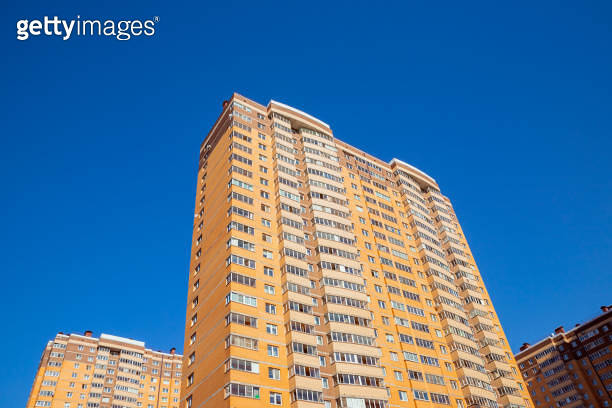 brown orange brick wall of multi-storey apartment building on blue sky ...