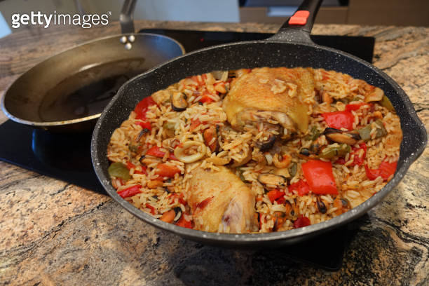 Paella being cooked Spicy rice chicken seafood and assorted vegetables ...