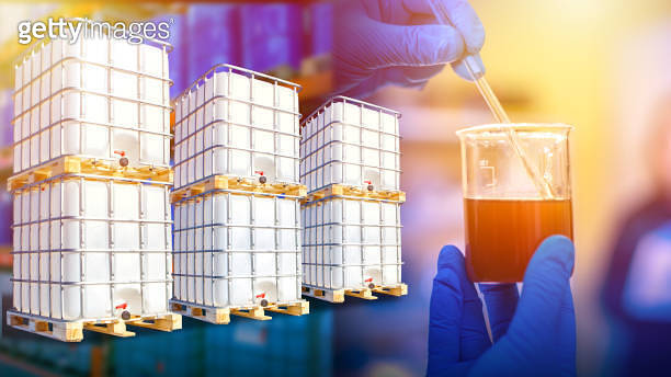 Large fluid storage tanks. Laboratory assistant hands with test tube ...