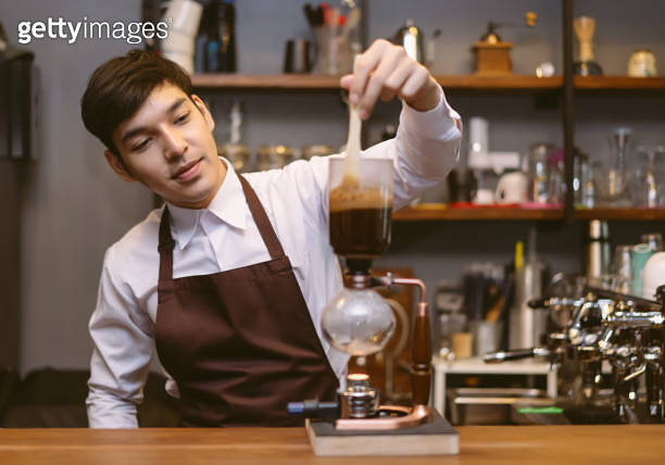 Handsome barista Asian man making coffee in syphon device for coffee ...