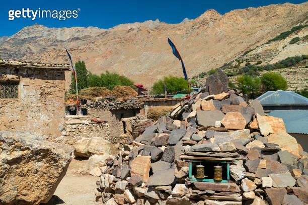 Ancient village with religious Buddhist stone mound and prayer wheels ...