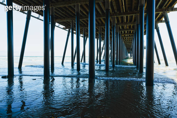 Under the pier. A long wooden pier, and ocean waves, a dramatic scene ...