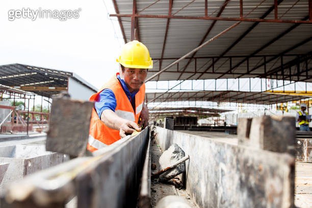 Construction engineer using measuring tape to measure a concrete bar ...