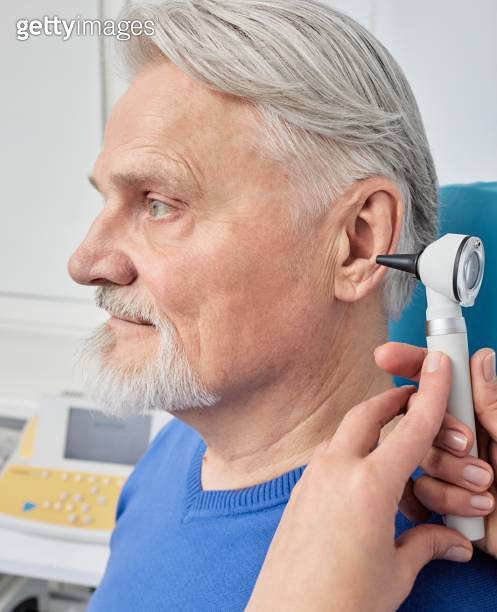 Elderly man while ear test with audiologist with otoscope at medical ...