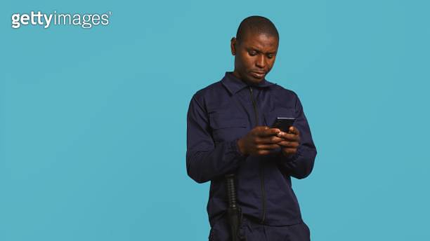 Security guard using smartphone, taking break during protection job ...