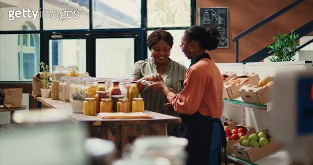 Retailer gives food samples to her customer in zero waste store 이미지 ...