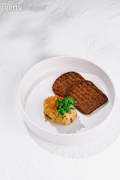 Chicken liver pate with mango puree and rye bread on white plate ...