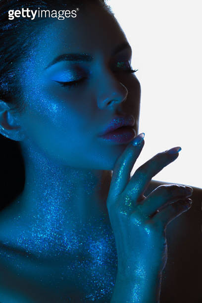 Woman with blue powder on her face, creating a vibrant and striking ...