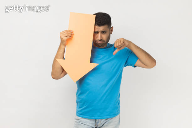 Disappointed man holding paper arrow indicating down, sad expression ...