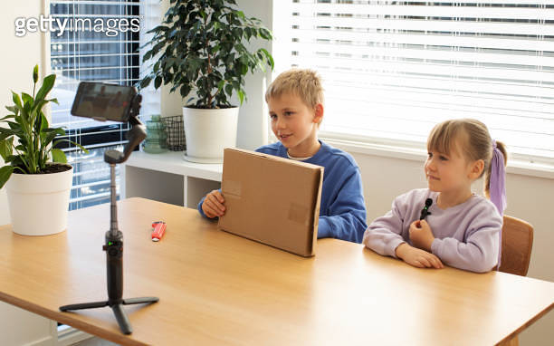 Kids recording an unboxing video for their vlog, smiling and excited as ...