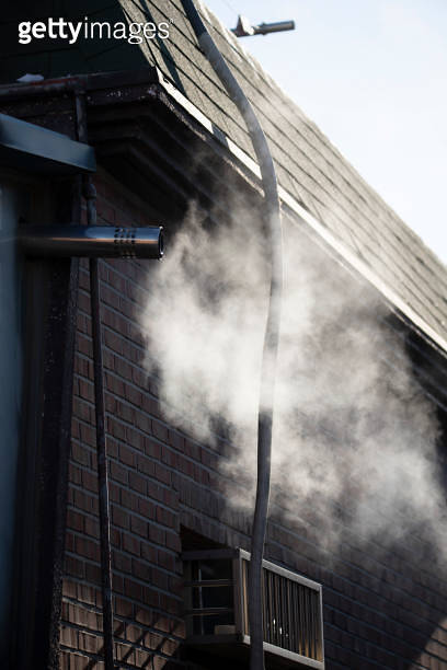Steam coming out of a central heating flue on a house wall in South ...