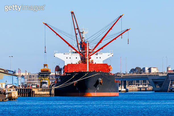 Large bulk carrier cargo ship loading/unloading at port on sunny day ...