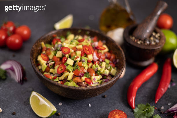 traditional salsa dip snack in wooden bowl on a table with ingredients ...