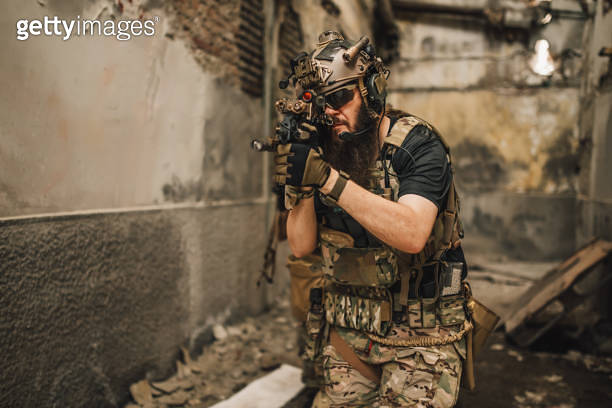 Portrait of soldier with sniper rifle shooting towards camera on ...