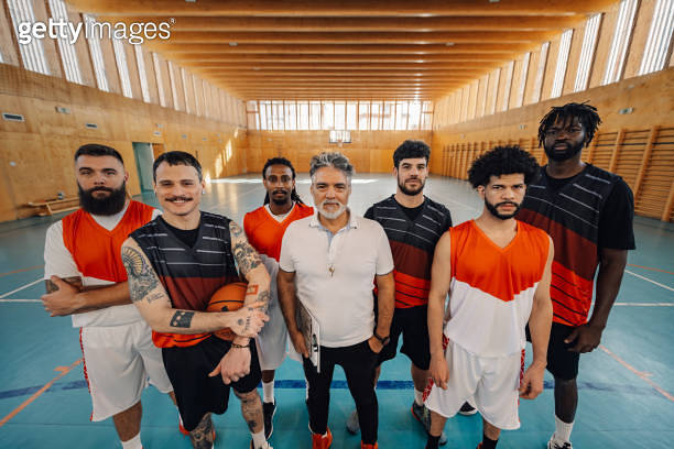 Portrait of diverse basketball team with senior coach posing on court ...