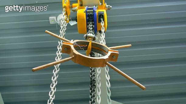 Detailed view of mechanical hoist with chains in industrial environment ...