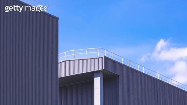Gray corrugated metal factory buildings with steel fence on rooftop in ...
