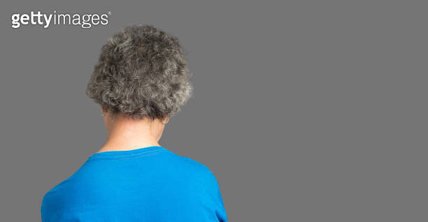 Back view of a senior woman suffering neck pain and neck tilt while ...